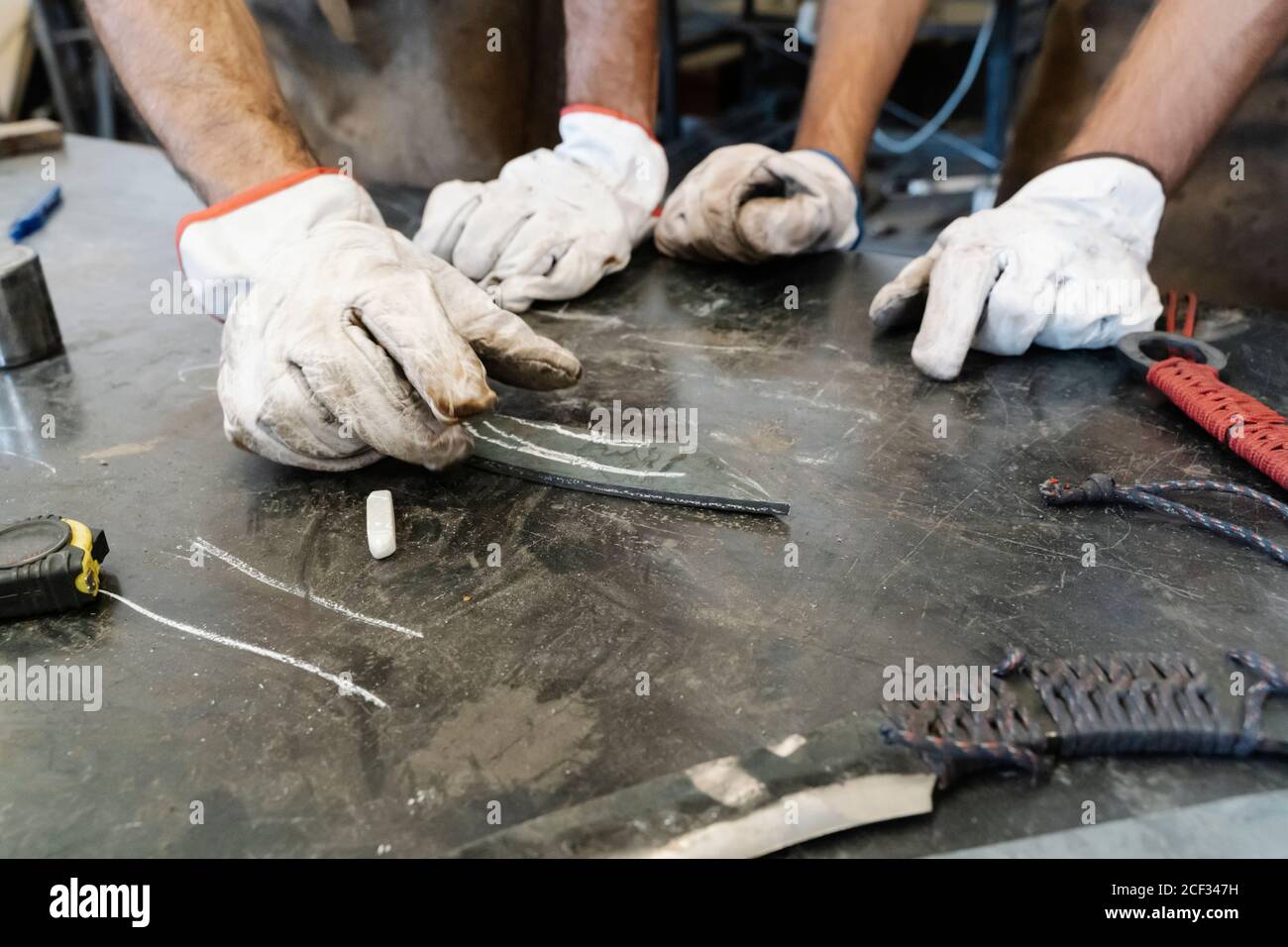 Group of blacksmiths making knives while standing at metal workbench in old garage Stock Photo ...