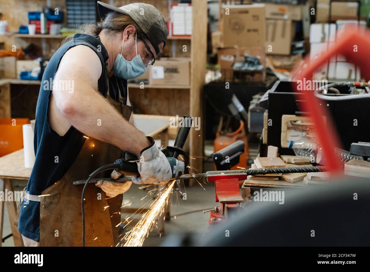 Busy blacksmith cutting metal detail with grinder tool while working ...