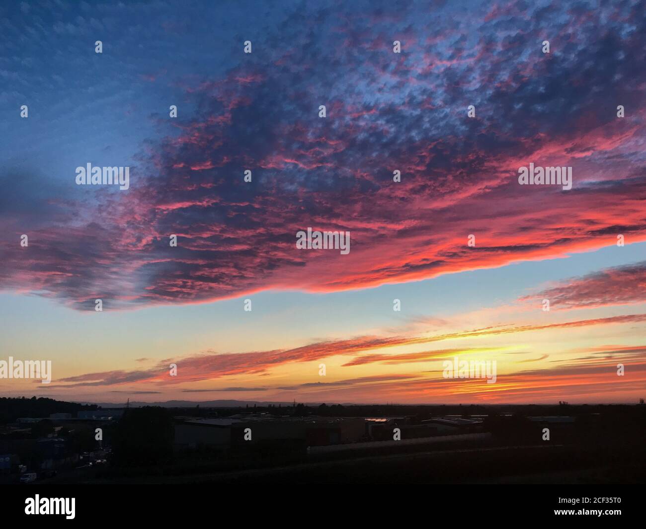 Colorful sunset with magenta clouds and a fiery orange glow of the sun ...