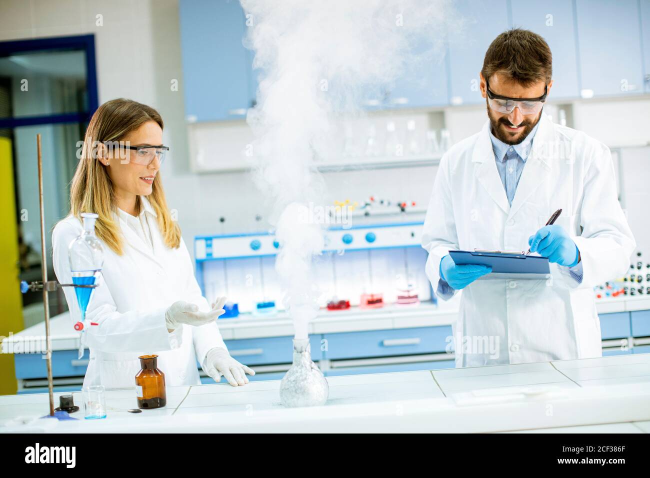 Young researchers doing experiment with smoke on a table of a chemical ...