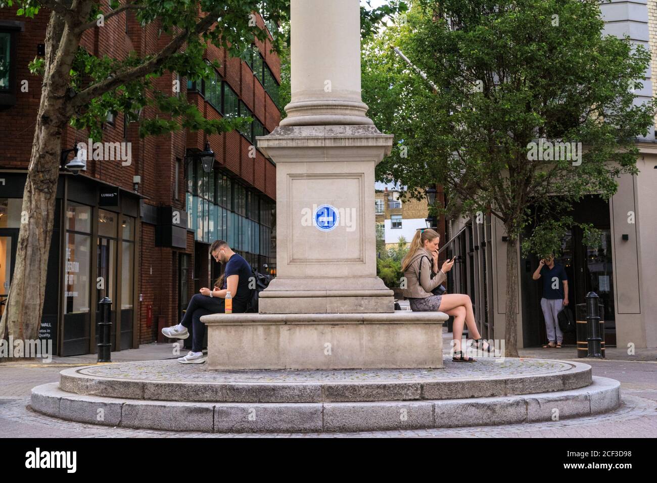 People sitting at the Seven Dials sun dial, tourist and shopping area ...