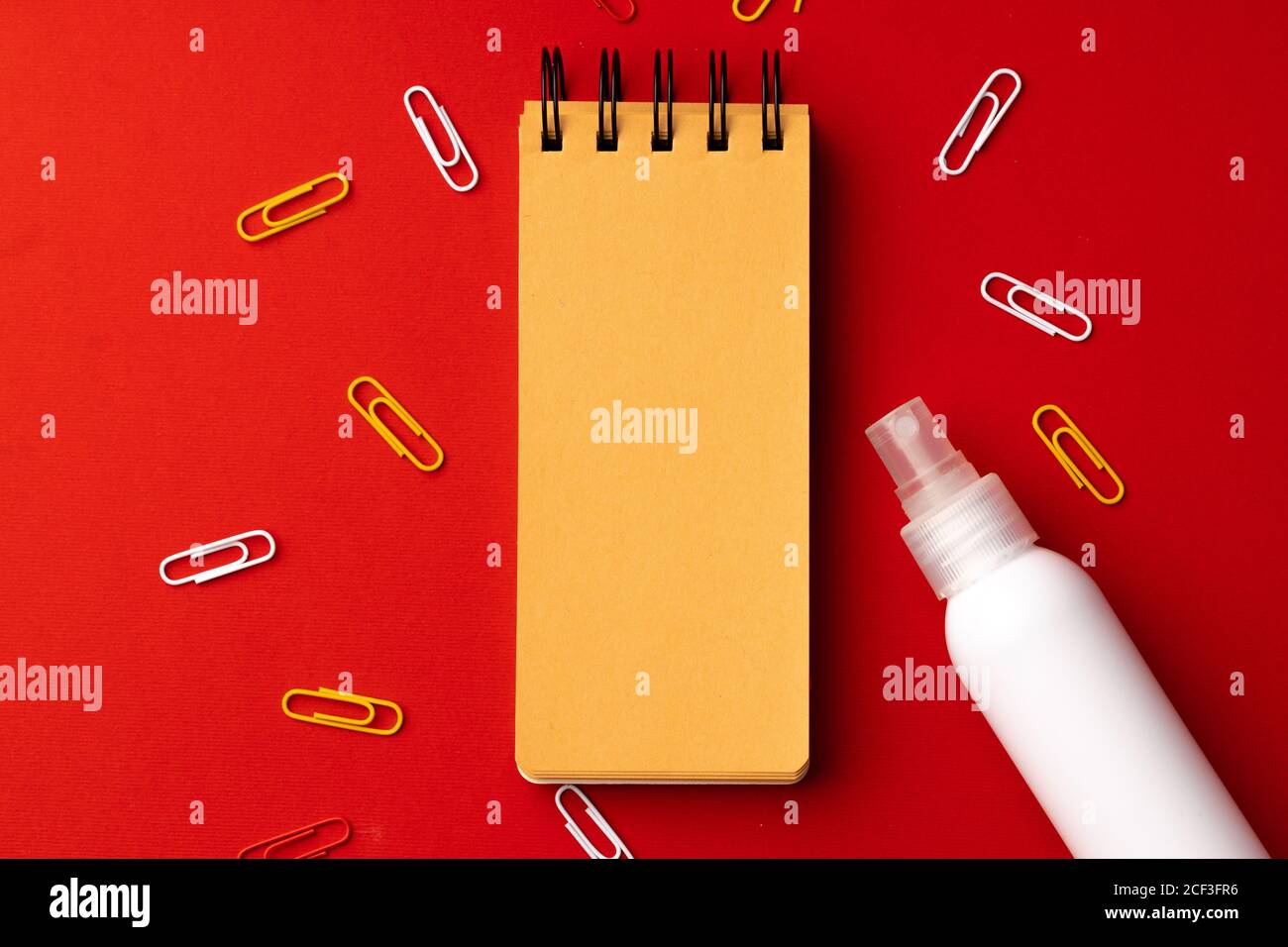 Small notepad with paper clips and spraybottle on red background Stock ...
