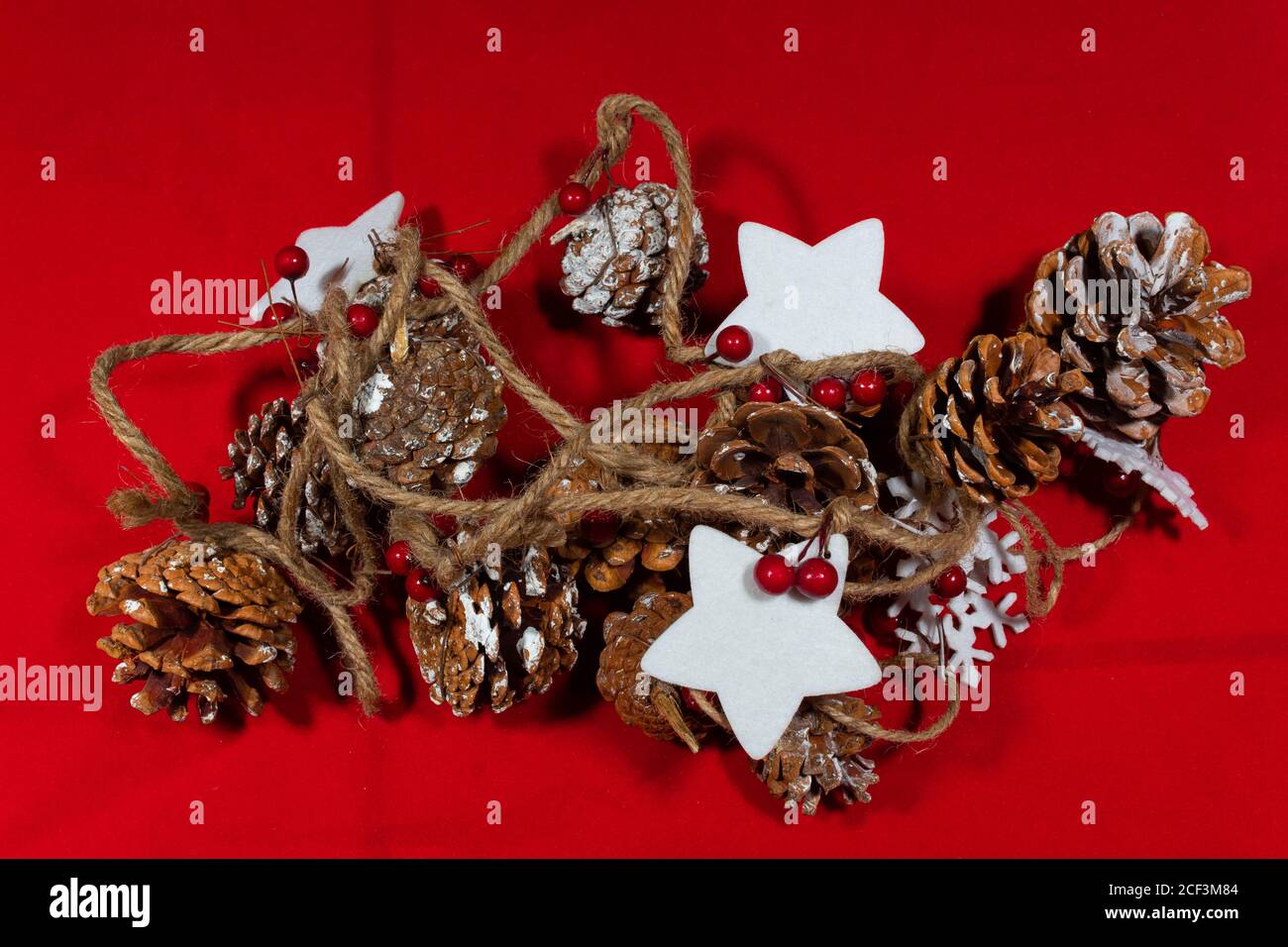 red christmas background with many pine nuts and stars tied to a rope ...