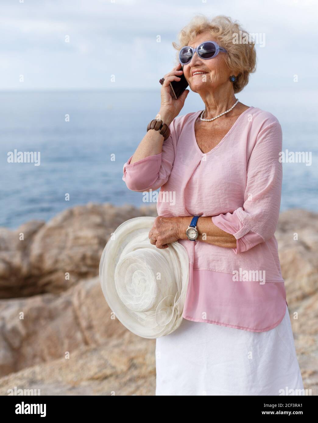Portrait of senior lady making phone call while resting at beach Stock ...