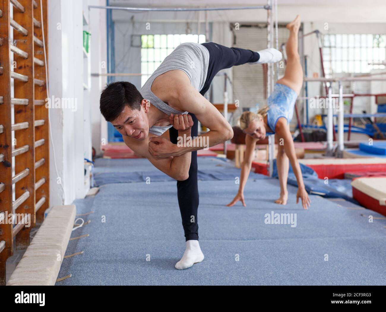 Man and woman doing acrobatic exercises on floor of gym Stock Photo - Alamy