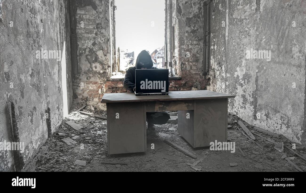 Hacker and laptop meaning safety data. Cyberterrorist in an abandoned ...