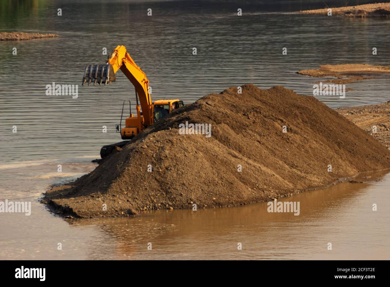 Excavator extracts sand and pebbles from a river in Southeast Asia ...