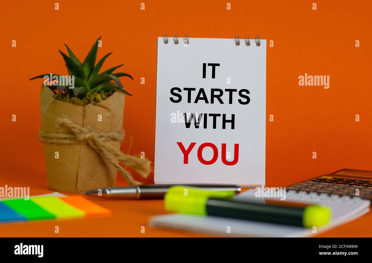 White note with inscription 'it starts with you' on beautiful orange ...