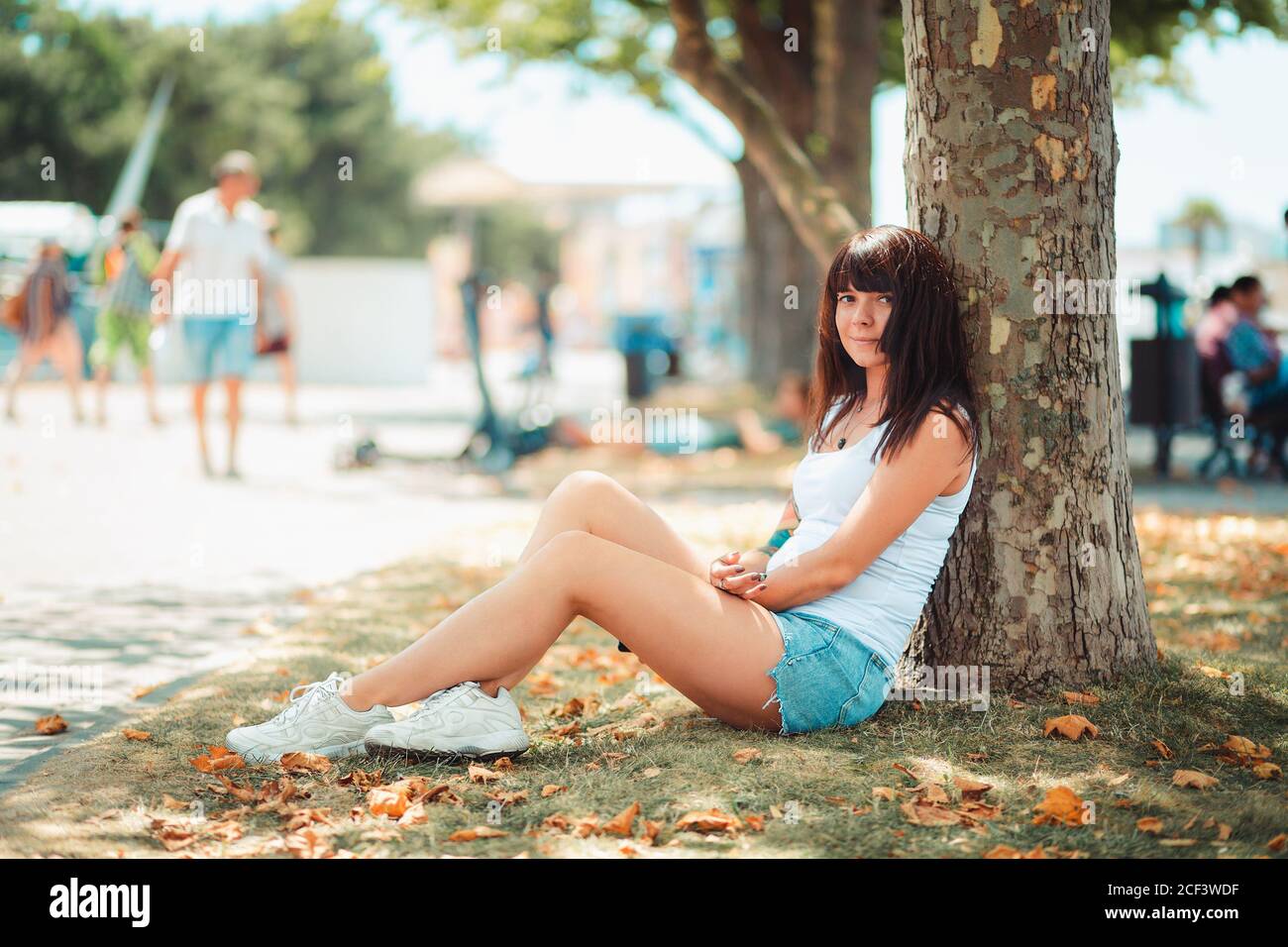 Woman sitting against tree trunk hi-res stock photography and images ...