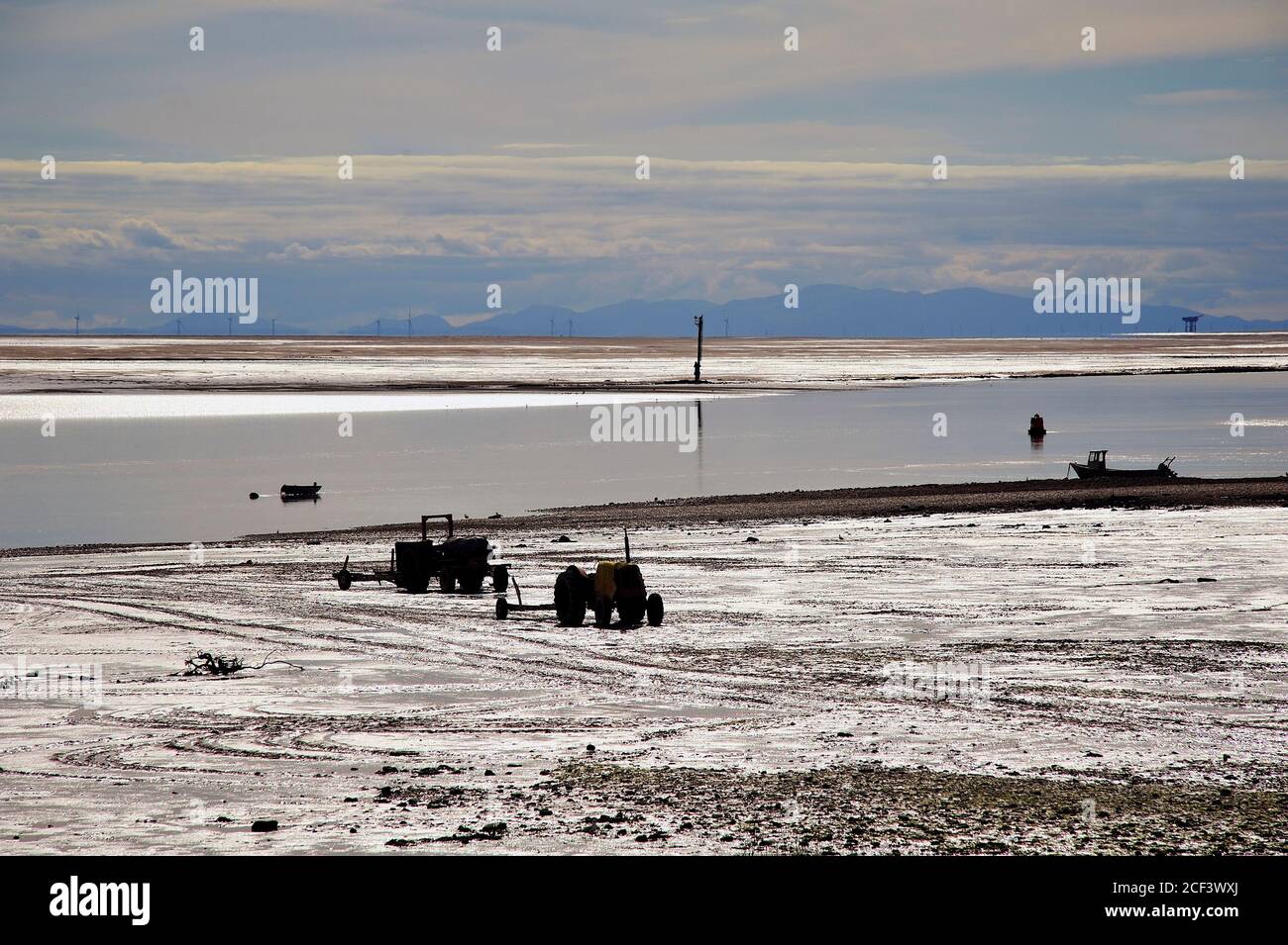 Silhouettes of tractors and boats on the River Ribble estuary at Lytham ...