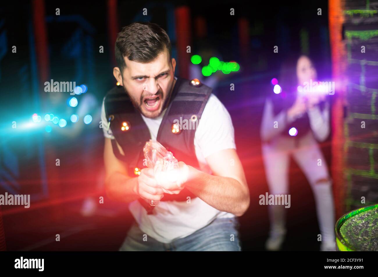 Emotional guy playing laser tag with friends on dark labyrinth in ...
