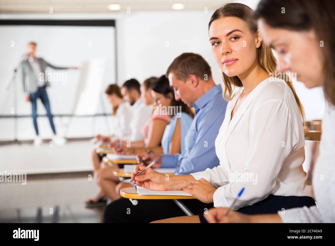 Side view of intelligent girl sitting with her fellow students in ...