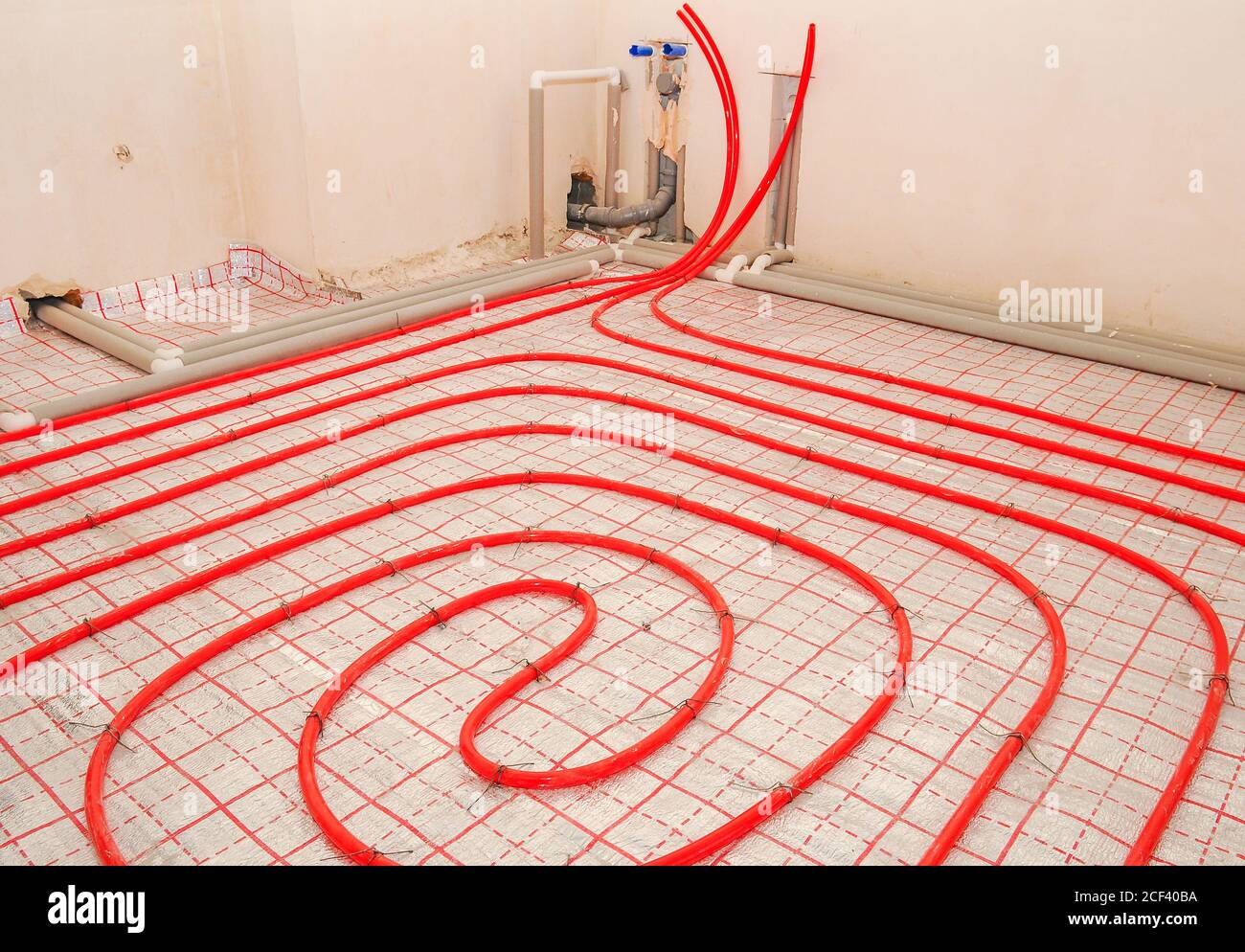 Installation water underfloor heating pipes on the silver reflective material in house ...