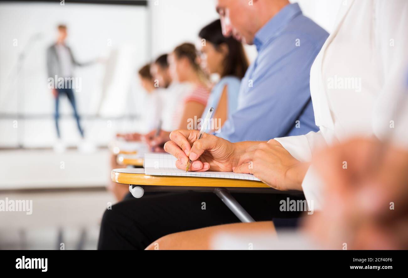 Focus on female hand writing in notebook during seminar in lecture hall ...