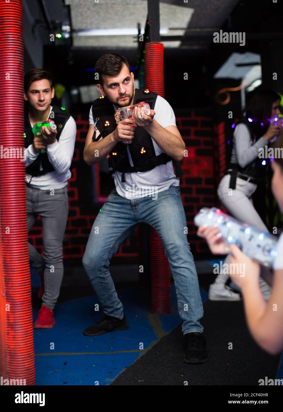 Excited guy aiming laser gun at other players during lasertag game in ...