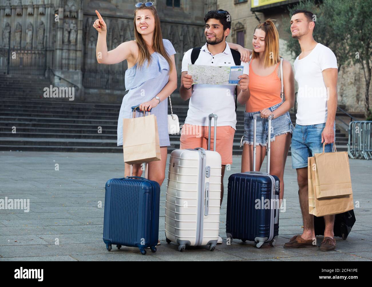 four active travelers holding map in hands and looking for their way in ...