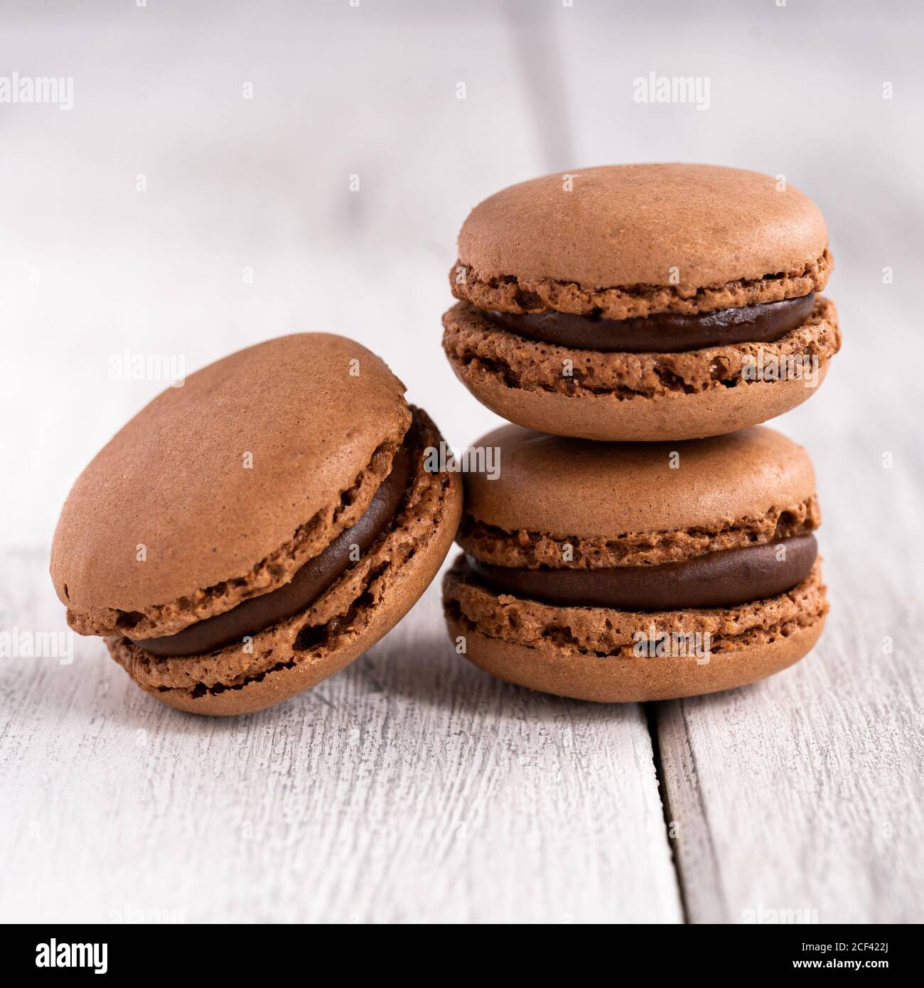 Colorful tasty macaroons stacked in pile against wooden white surface ...