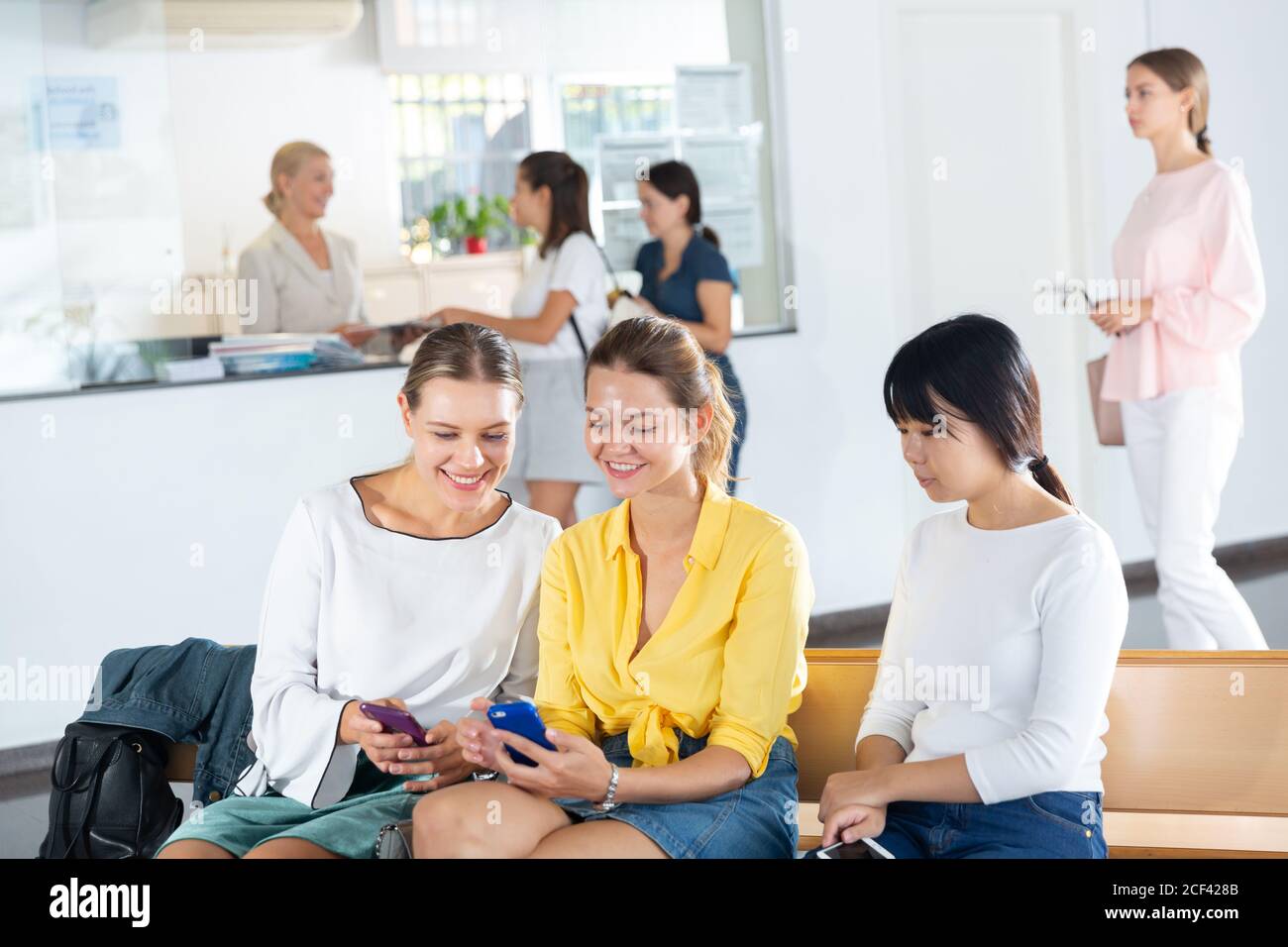 Female students talking and using smartphones, spending time together ...