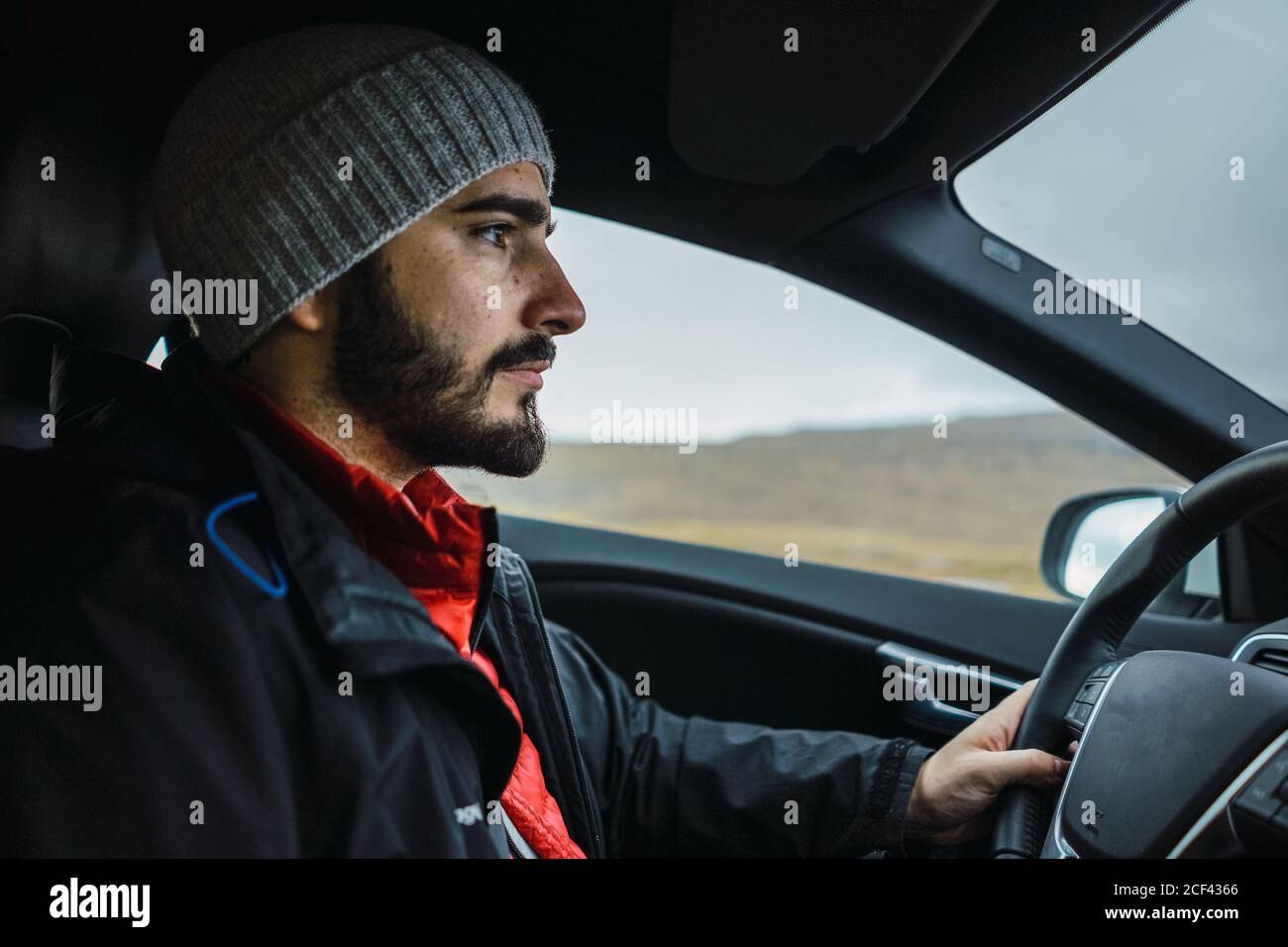 Side view of male driver riding car on countryside road during trip on ...