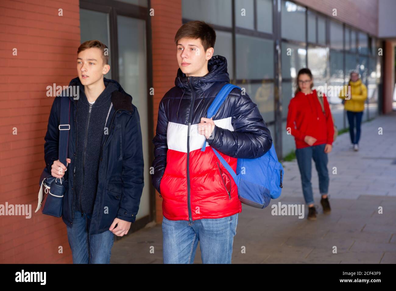 Two teen students walking together outside college building on spring ...