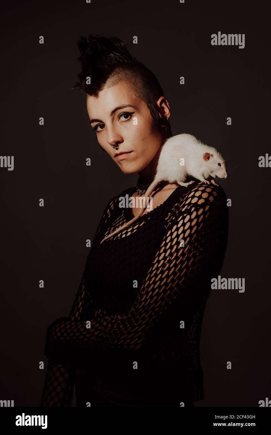 Confident Woman with mohawk carrying white rat on shoulder and looking ...
