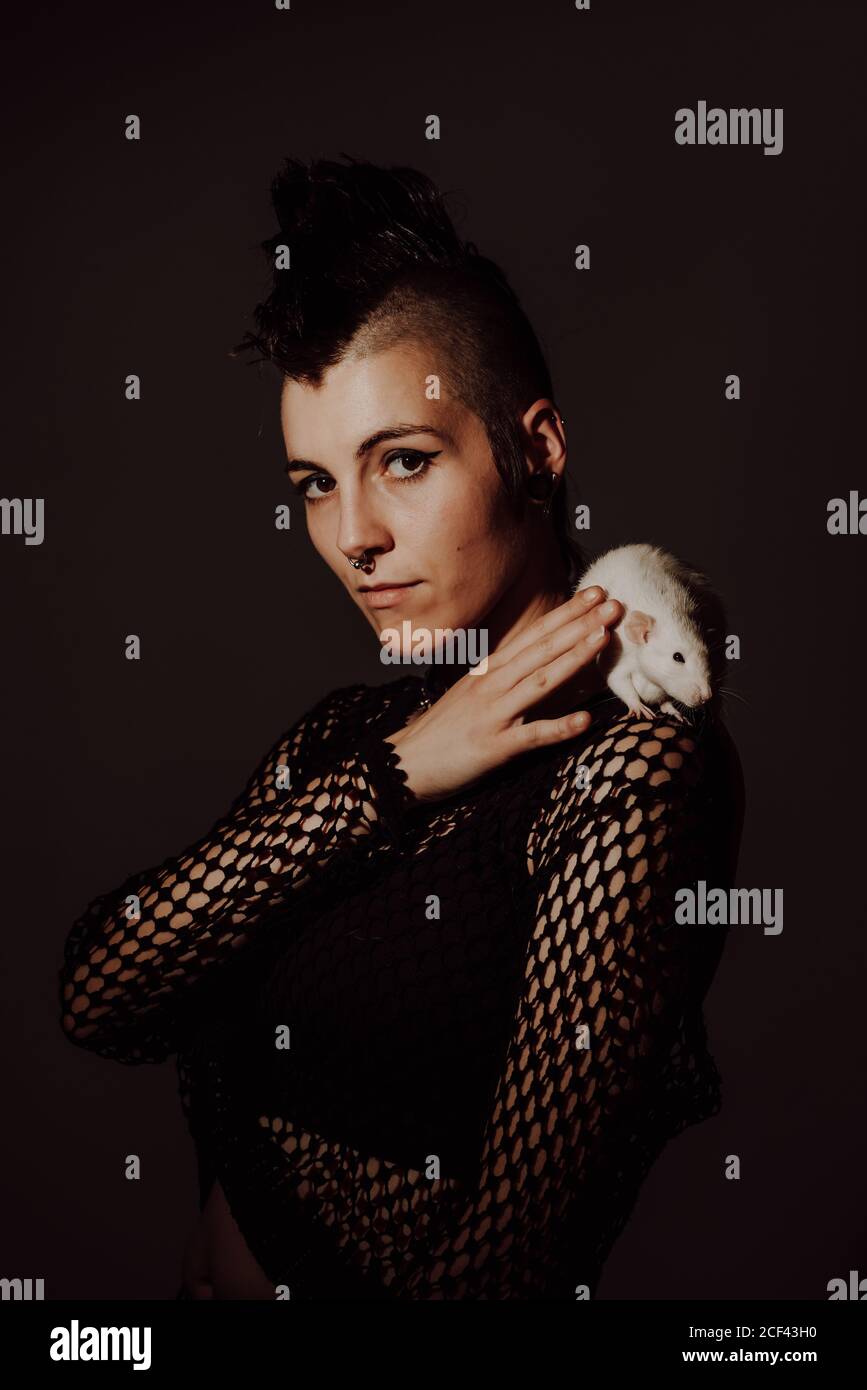 Confident Woman with mohawk carrying white rat on shoulder and looking ...