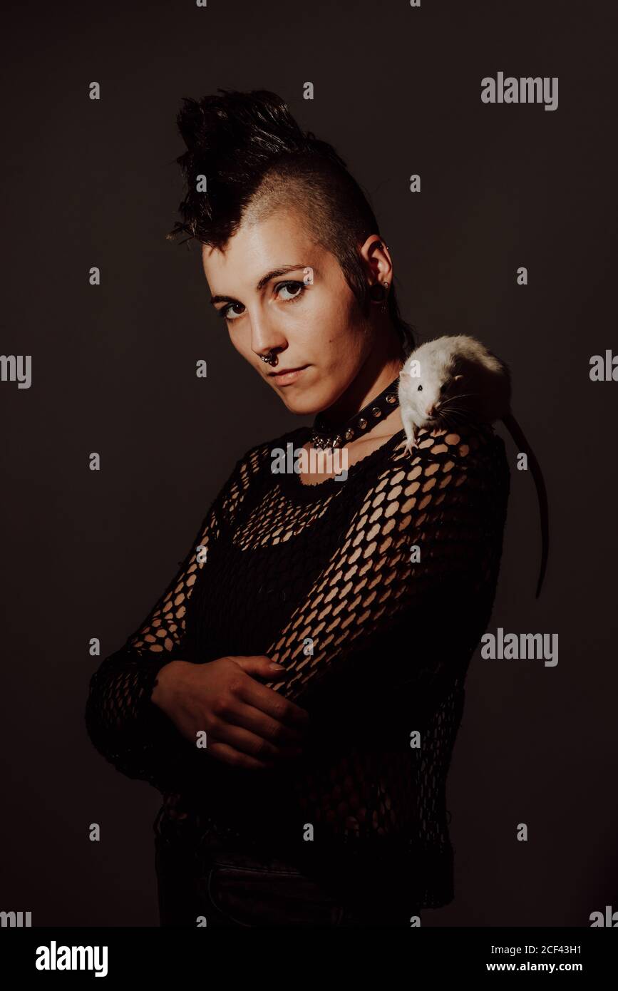 Confident Woman with mohawk carrying white rat on shoulder and looking ...