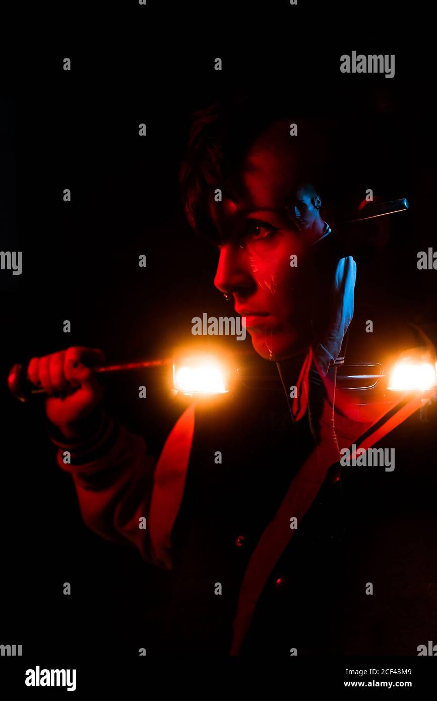 Side view of contemporary female in bomber jacket looking away holding ...