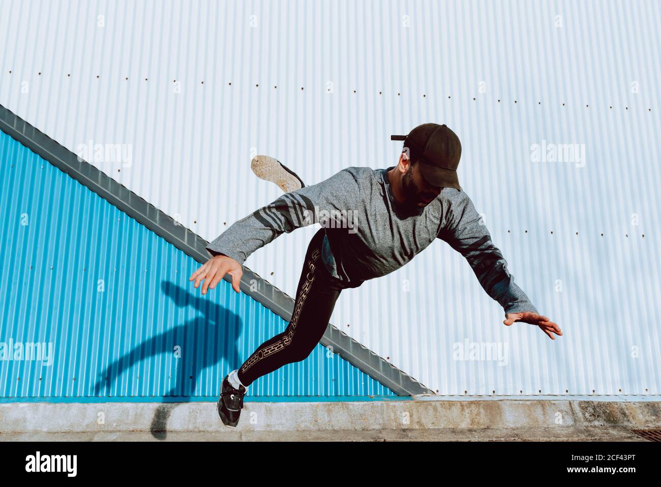barefoot guy in stylish outfit performing flip near wall of modern ...