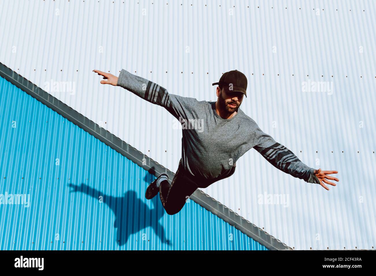 barefoot guy in stylish outfit performing flip near wall of modern ...