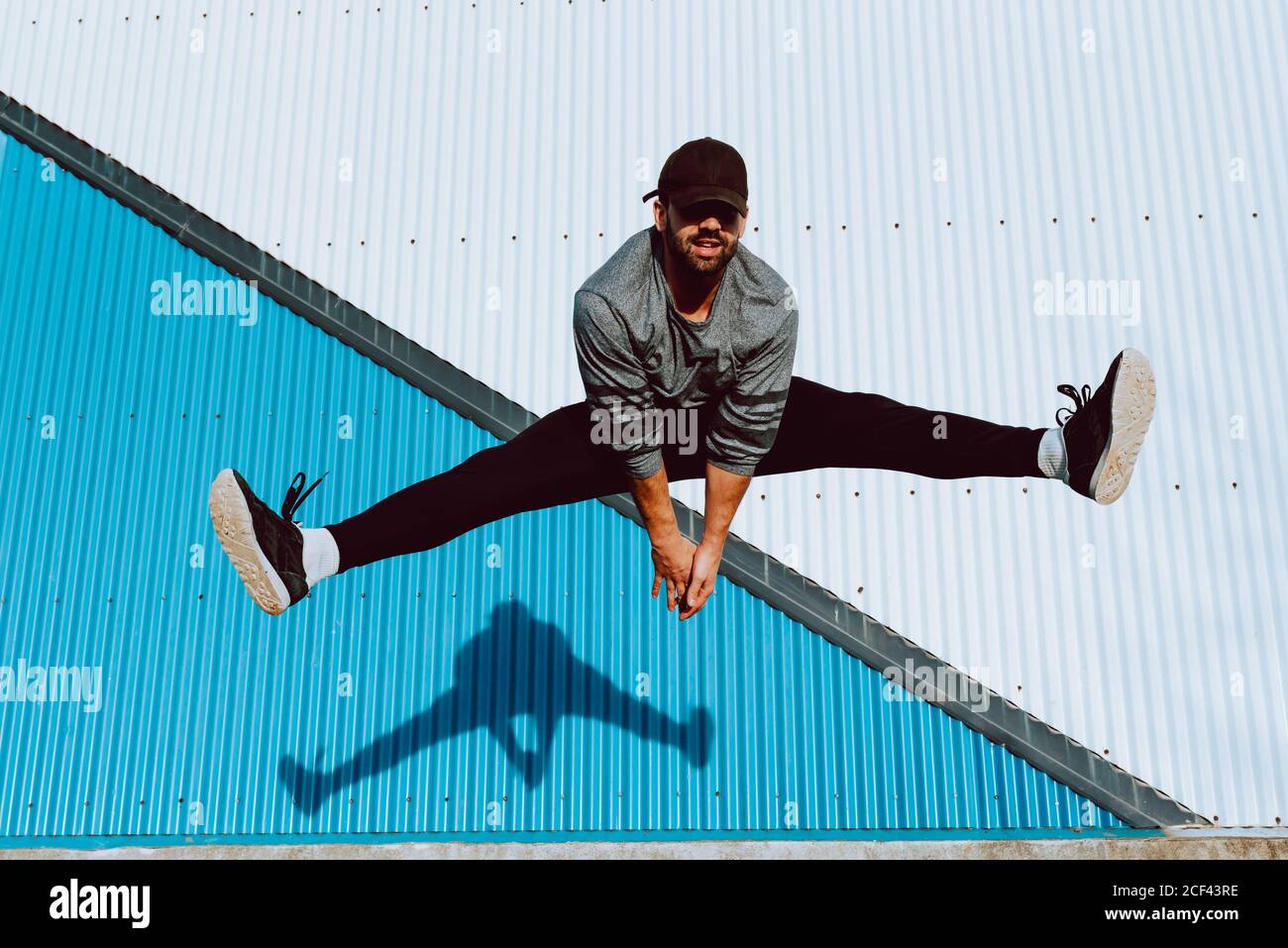 barefoot guy in stylish outfit performing flip near wall of modern ...
