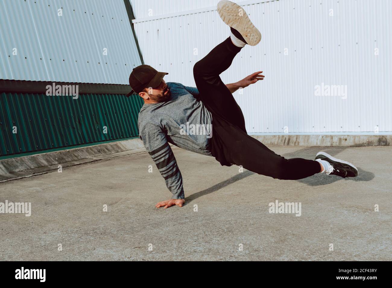Attractive guy performing handstand and while dancing near wall of ...