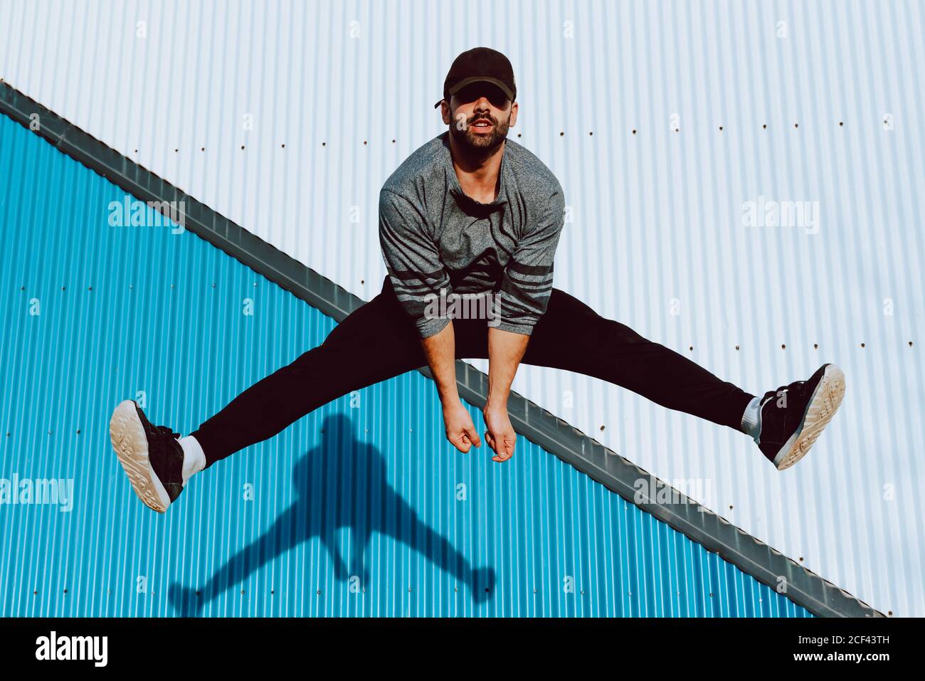 barefoot guy in stylish outfit performing flip near wall of modern ...