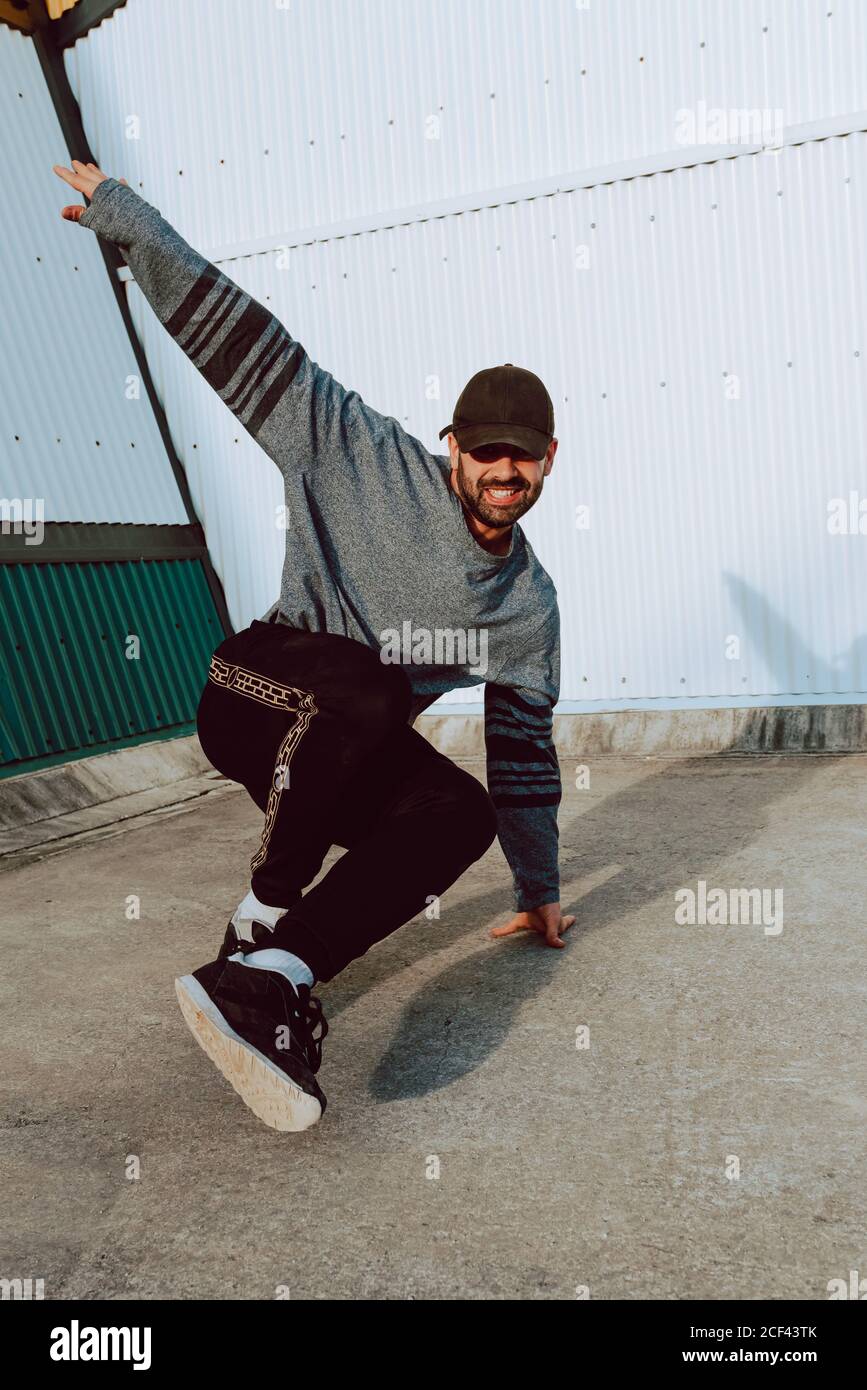 Attractive guy performing handstand and while dancing near wall of ...
