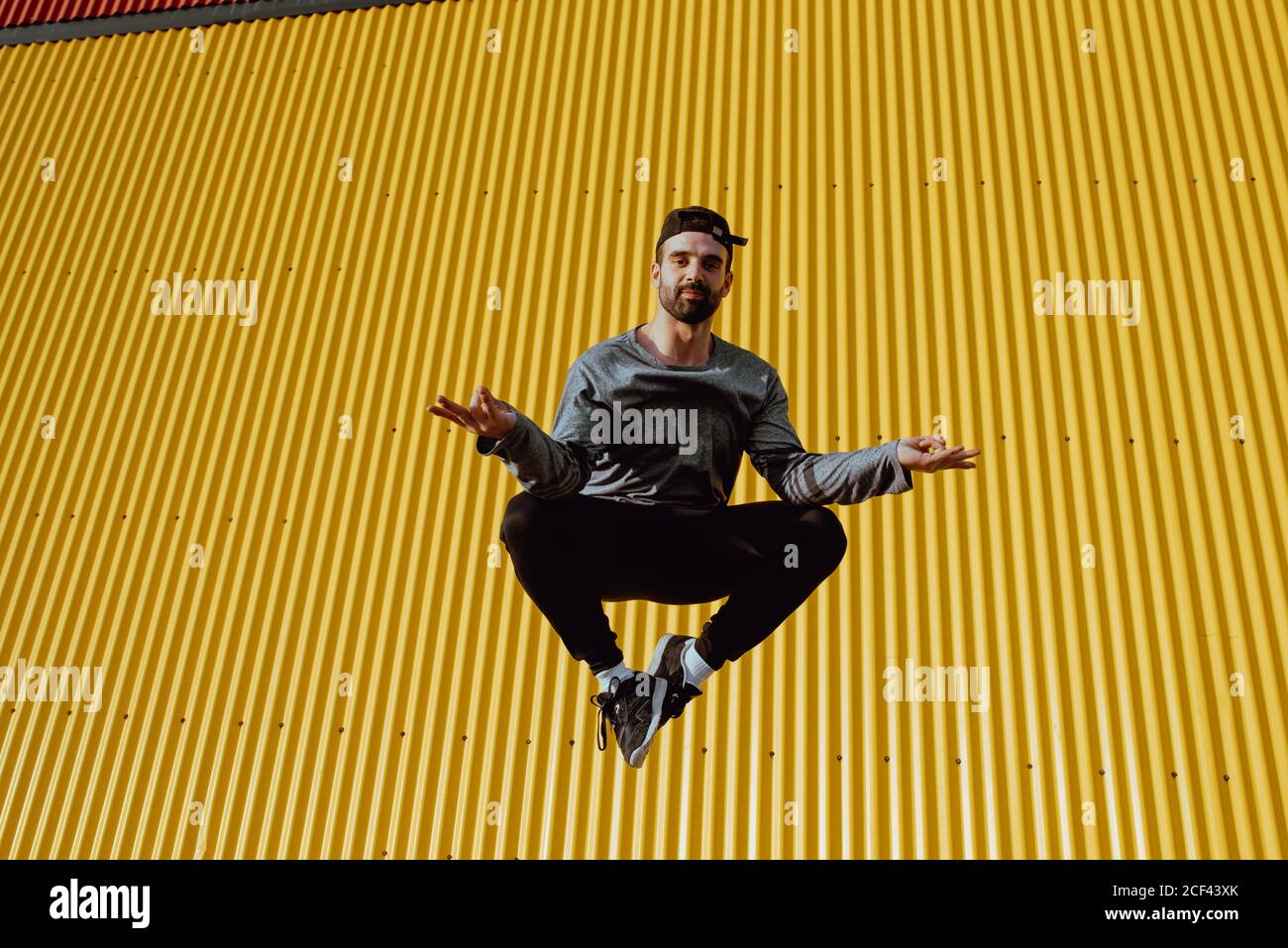 Handsome bearded guy in trendy outfit leaping up and looking at camera ...
