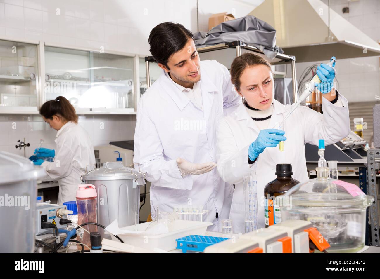 Two students performing experiments in university laboratory, using ...