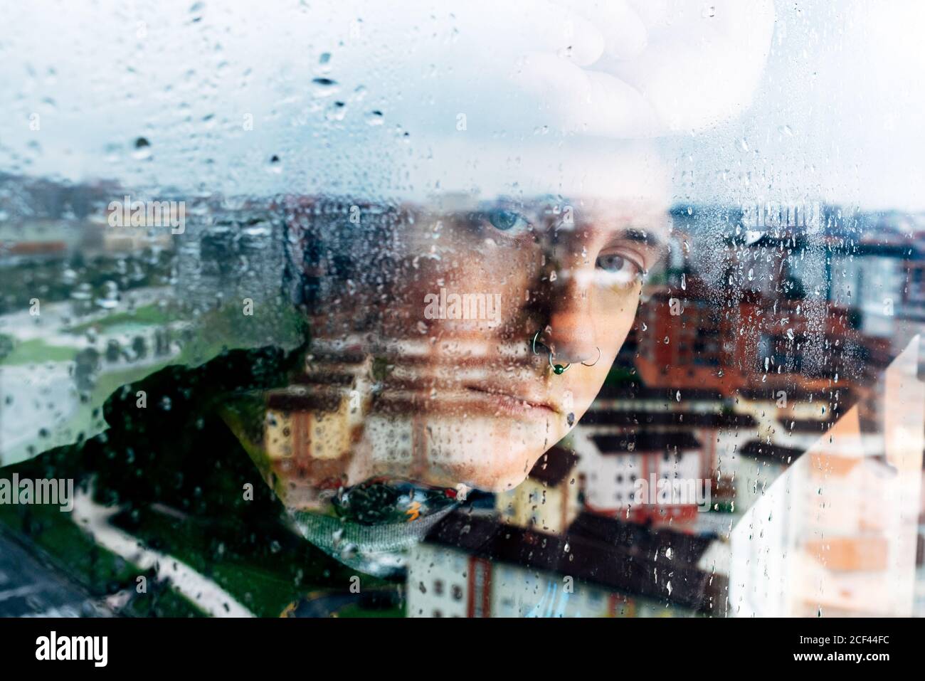 Depressed man looking through window Stock Photo - Alamy