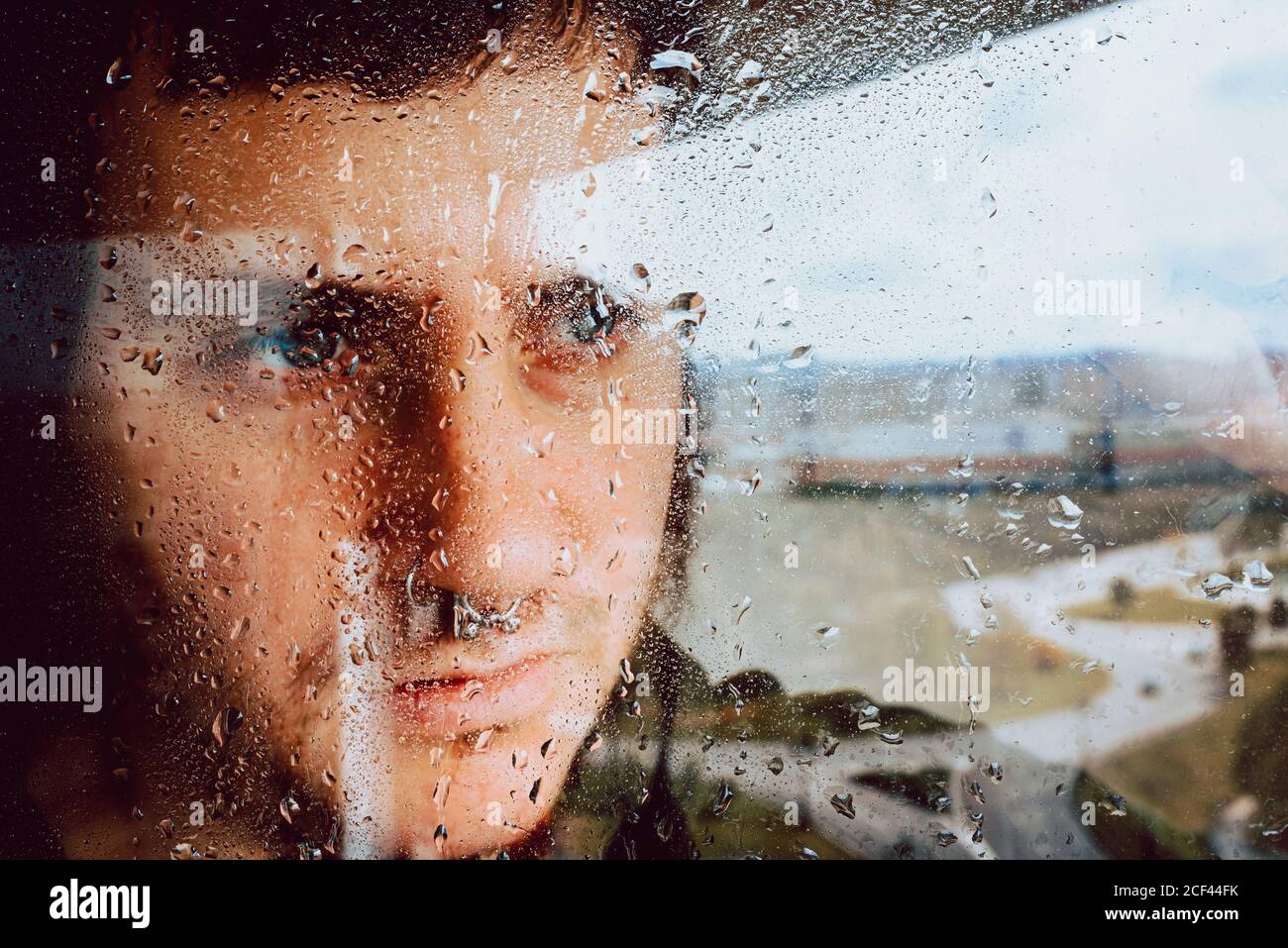 Depressed man looking through window Stock Photo - Alamy