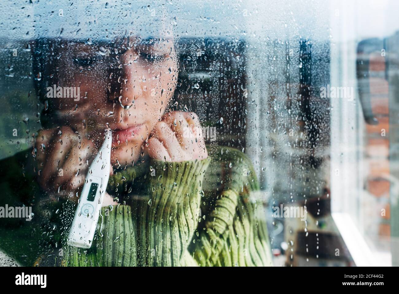 Sick Woman checking body temperature near window at home Stock Photo ...