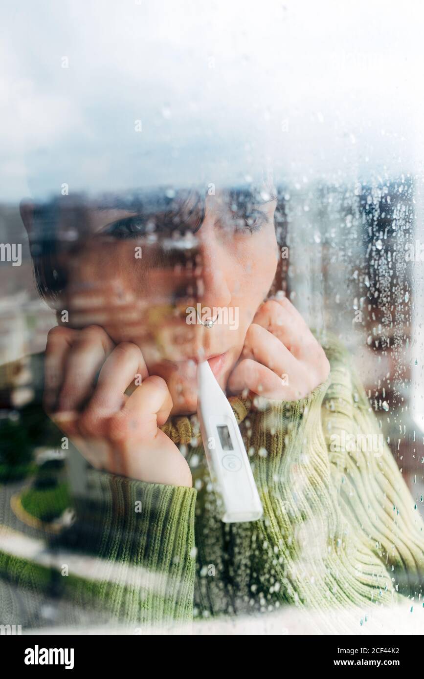 Sick Woman checking body temperature near window at home Stock Photo ...