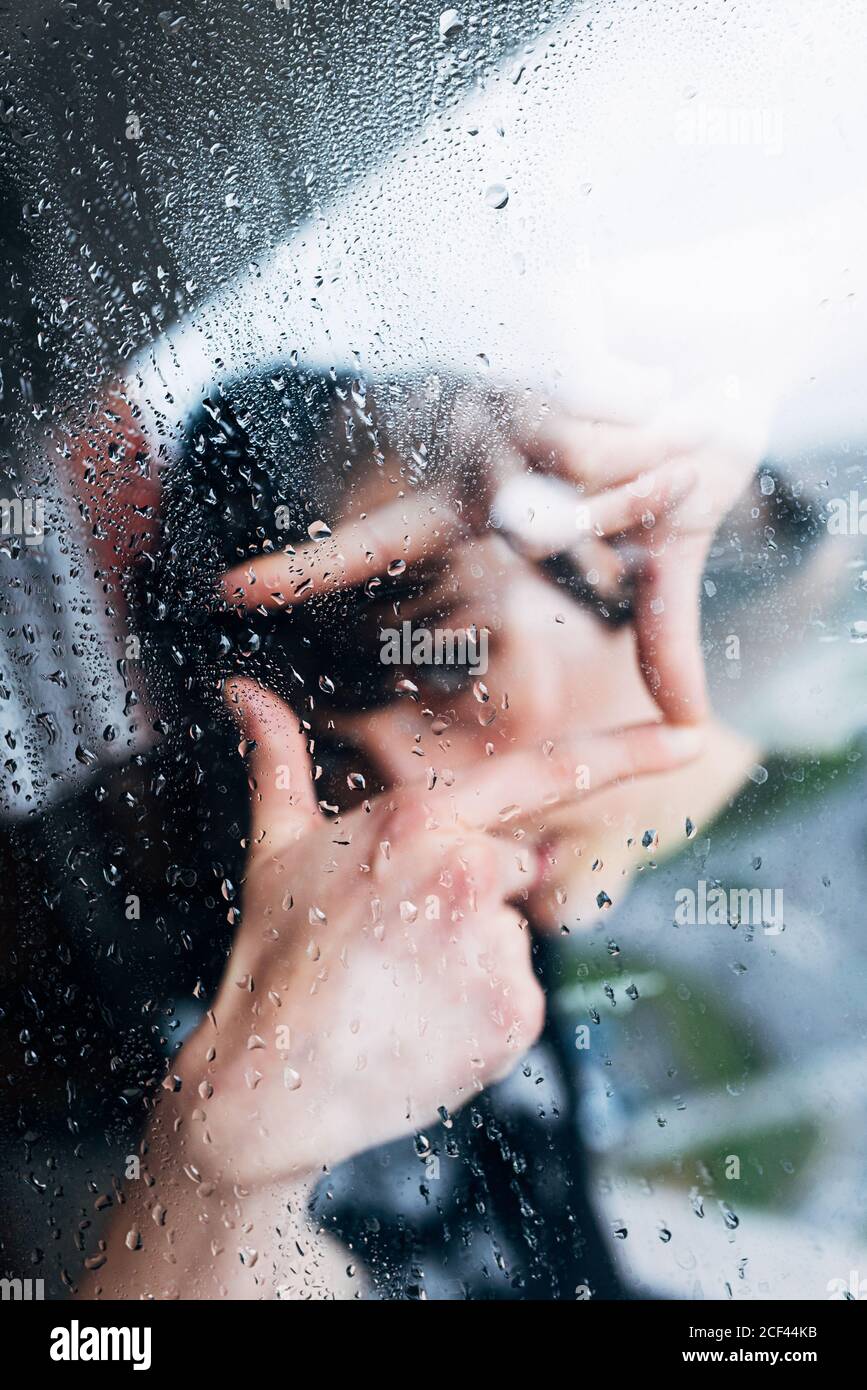 Young Woman looking through window in white room Stock Photo - Alamy