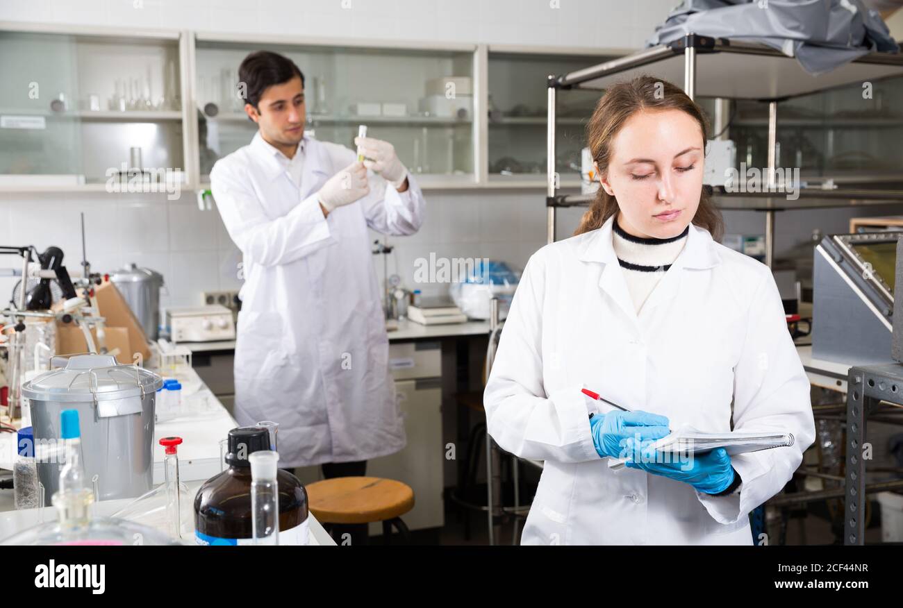Portrait of young woman lab technician writing report on results of ...