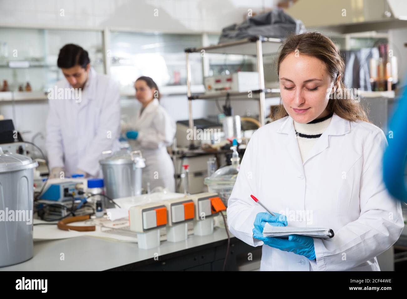 Portrait of young woman lab technician writing report on results of ...