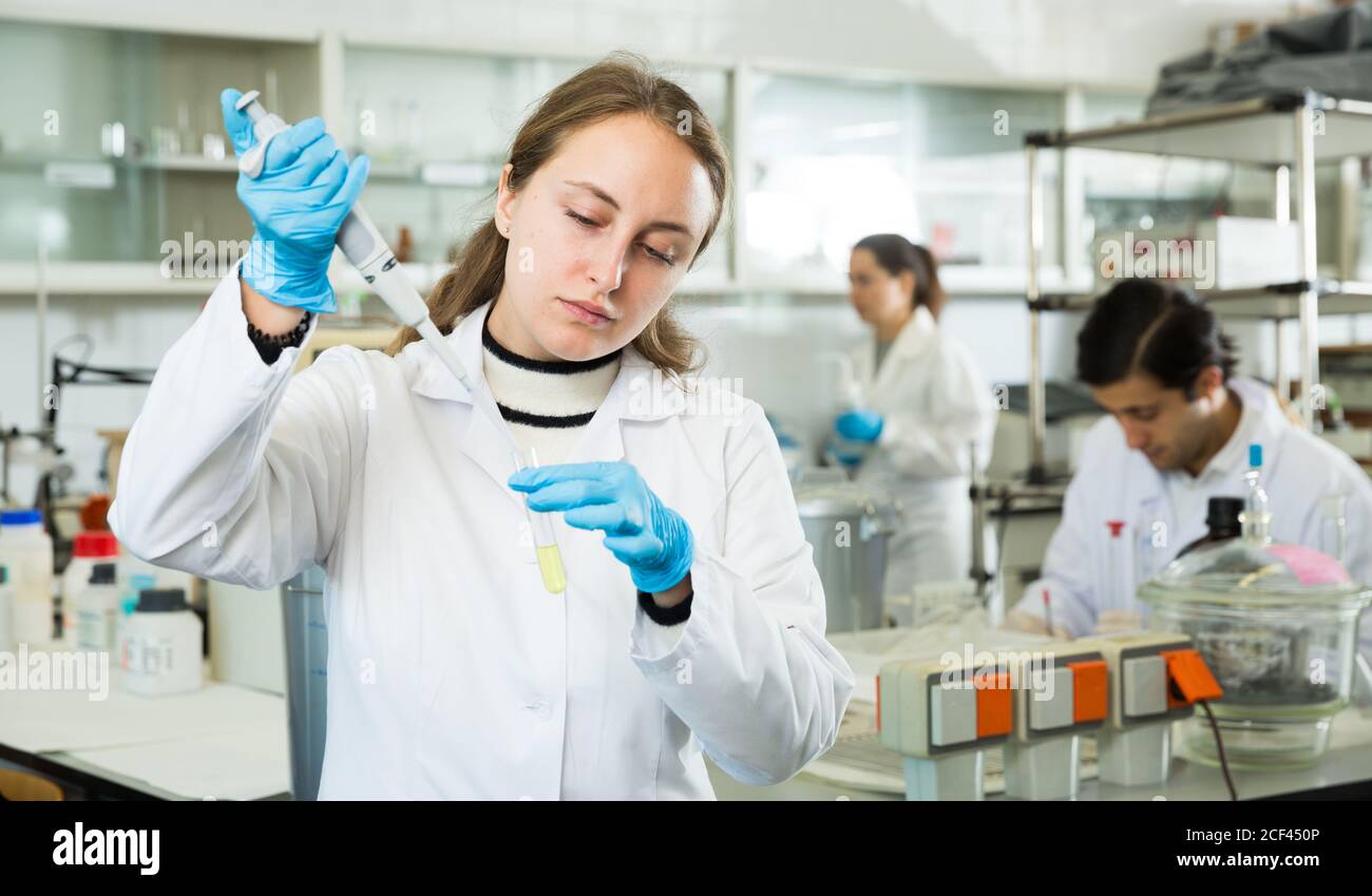 Female student performing experiments in university laboratory, using ...