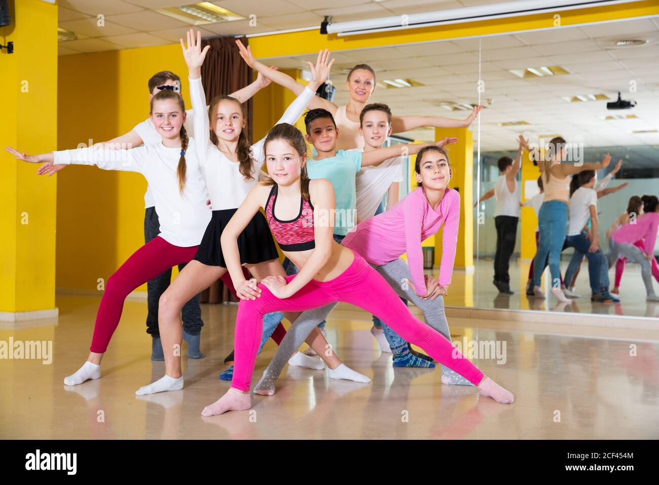 Happy tweens posing with young female coach during dance training in ...