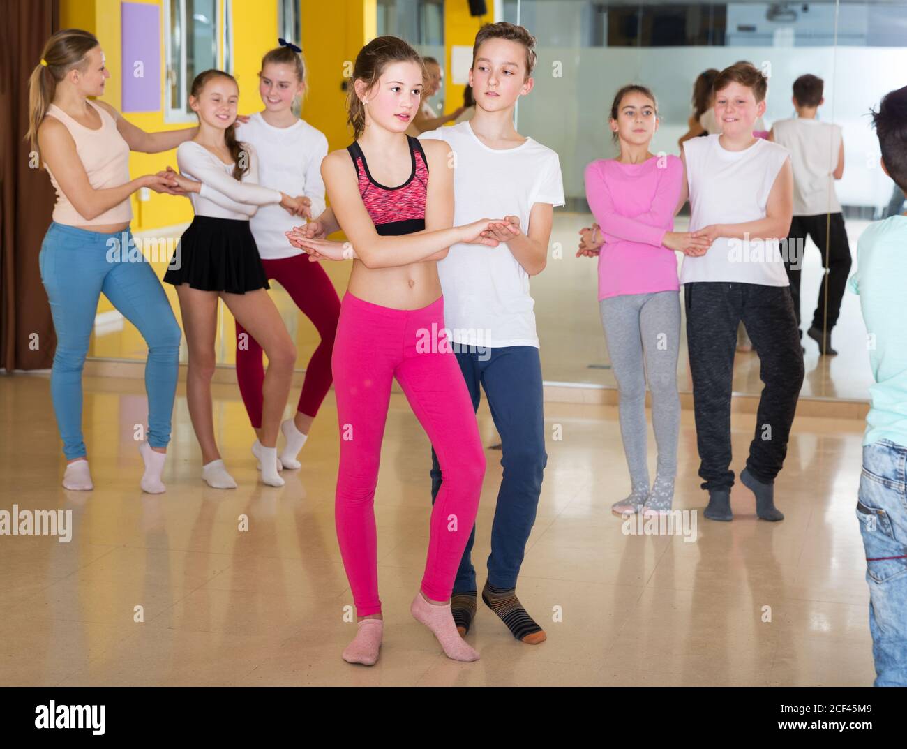 Group of tweens practicing vigorous jive movements in dance studio with ...