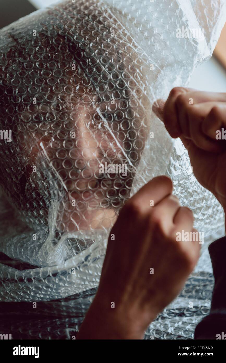 Scared Woman trying to free herself while entangled in bubble wrap ...