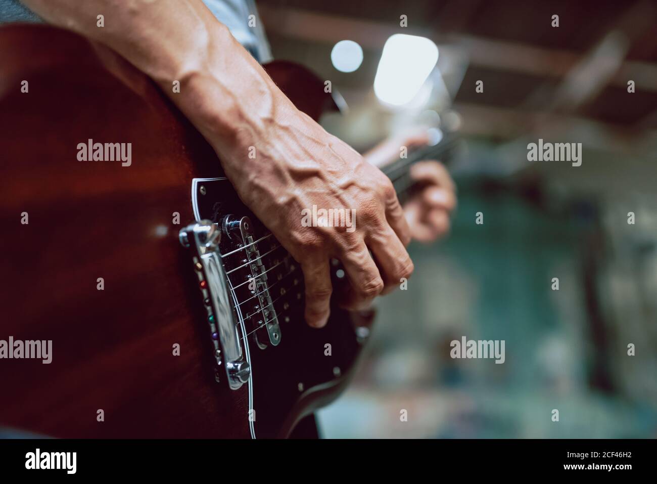 man clamping strings on guitar neck Stock Photo - Alamy