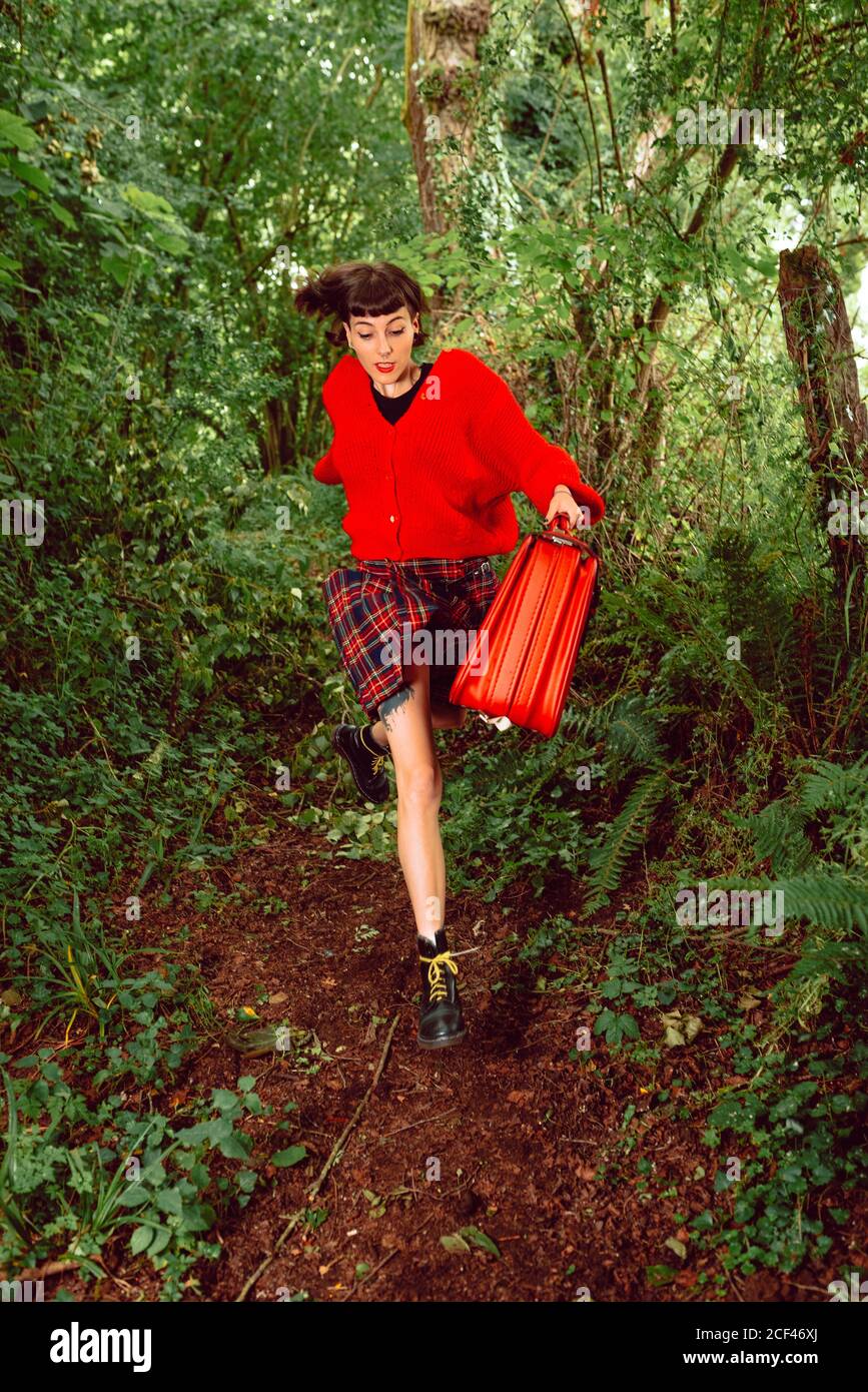 Woman in red with big red suitcase in forest Stock Photo - Alamy
