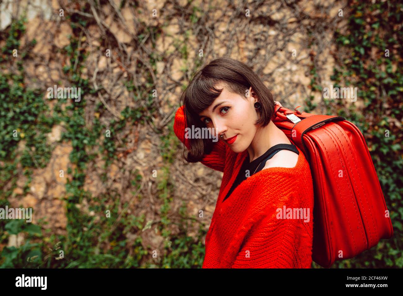 Woman in red with big red suitcase in forest Stock Photo - Alamy